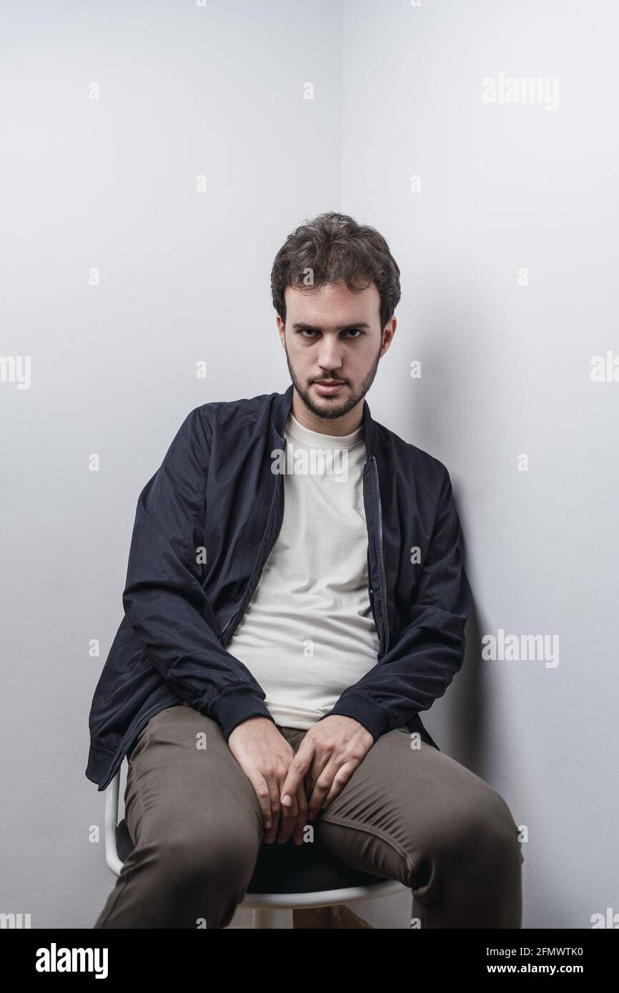 Vertical shot of a Caucasian man with an intense stare while seated on ...
