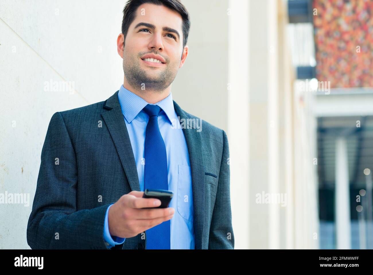 Handsome and confident businessman or manager talking on his business cell phone walking in ...