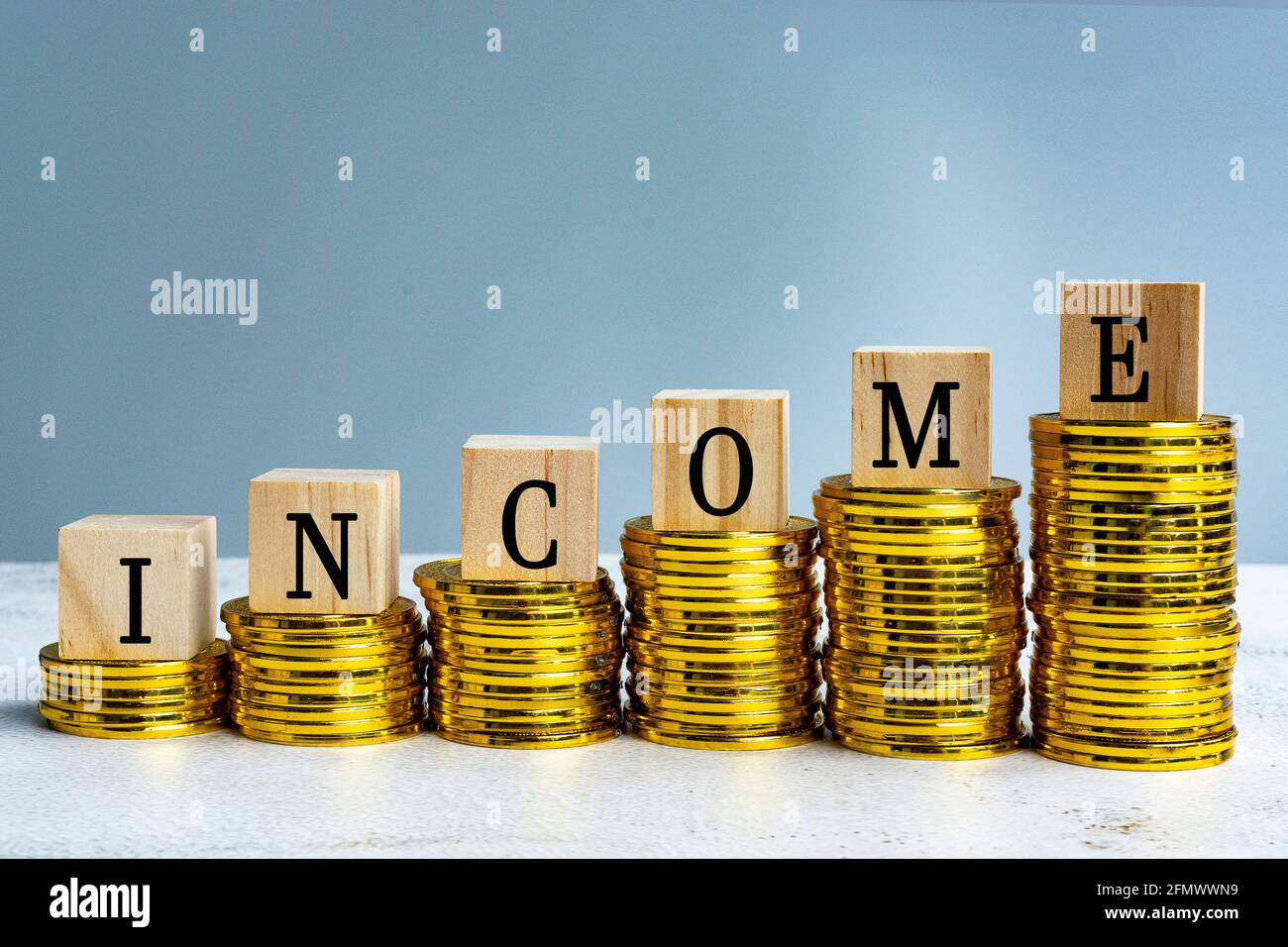 Income text on wood block with a pile of coins Stock Photo - Alamy
