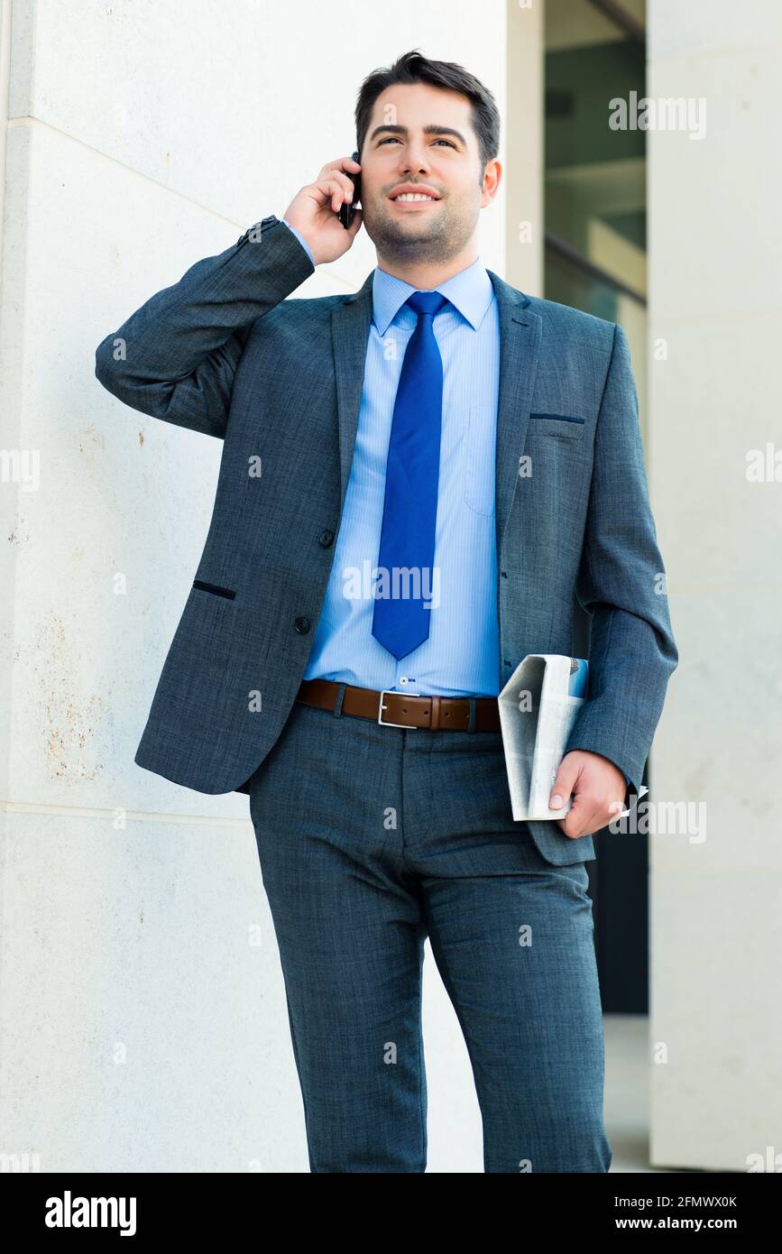 Handsome and confident businessman or manager talking on his business cell phone walking in ...