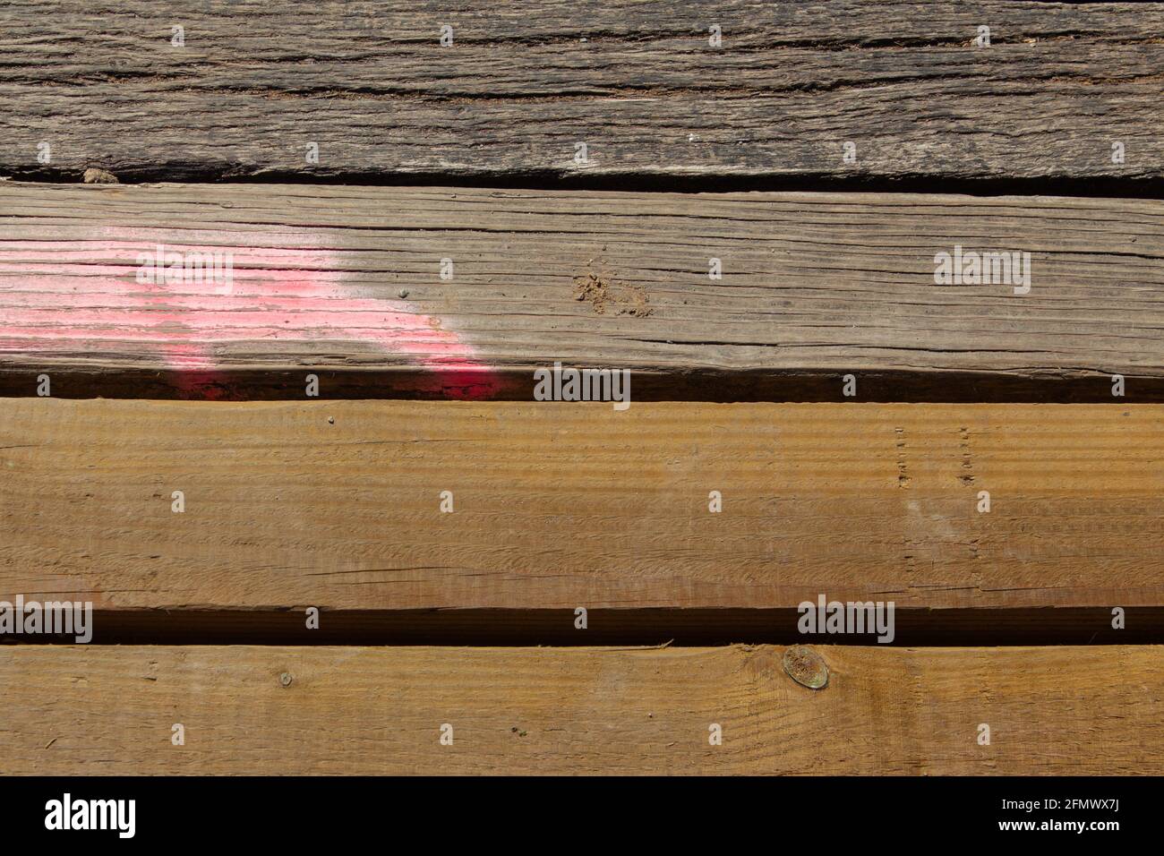 Damaged wooden planks with pink spray paint markings to mark as to ...