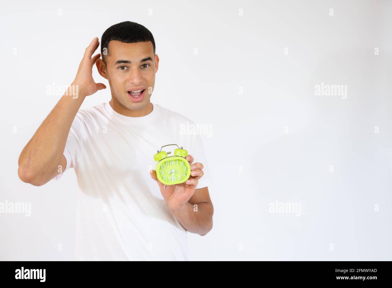 Surprised young man holding an alarm clock isolated over white ...