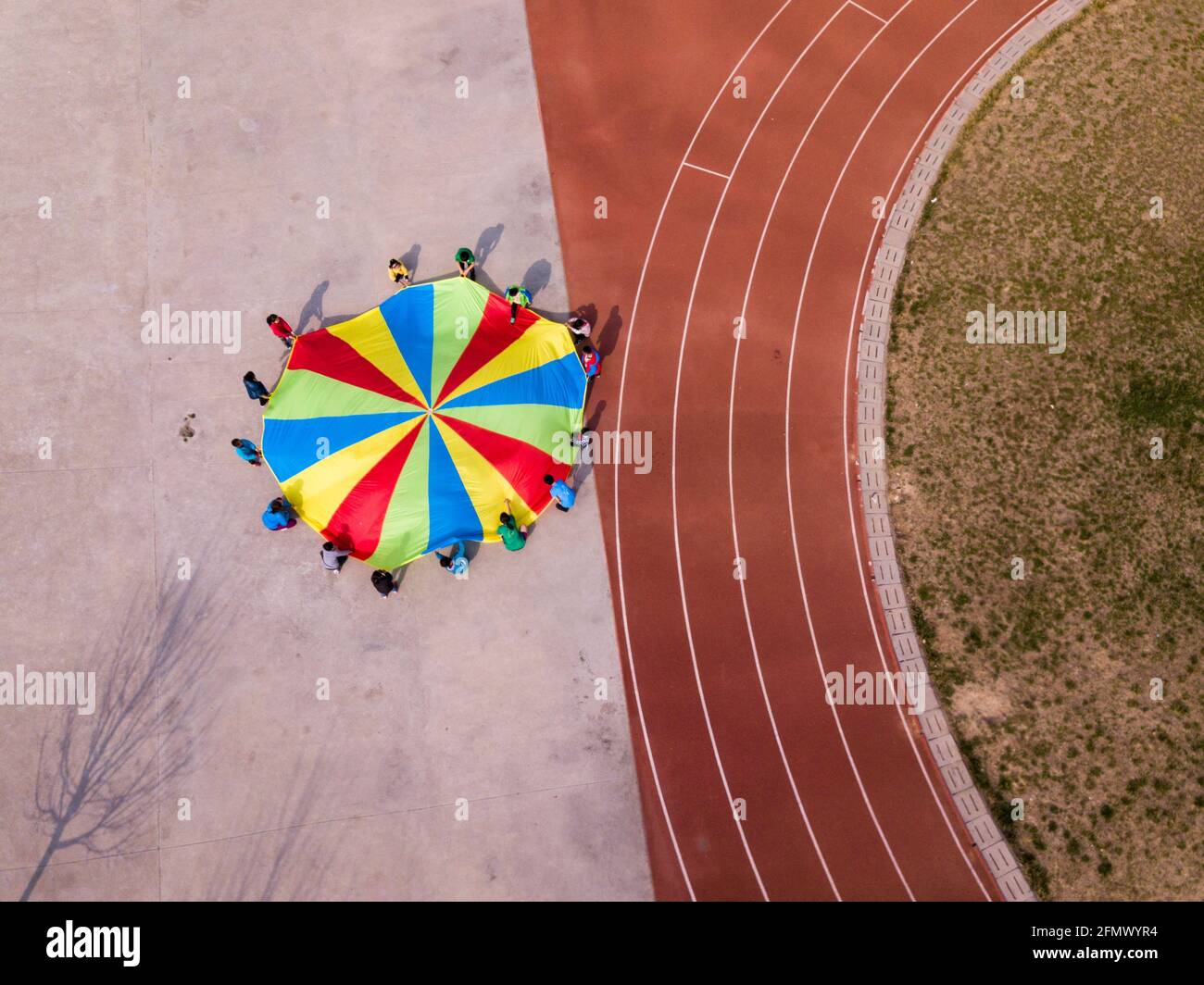 Aerial photo of a group of primary students playing with a parachute in ...