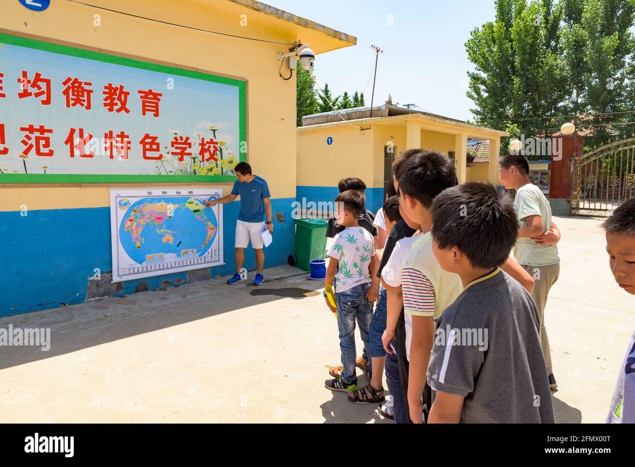 A teacher giving a geography lesson outdoors to primary students in a ...