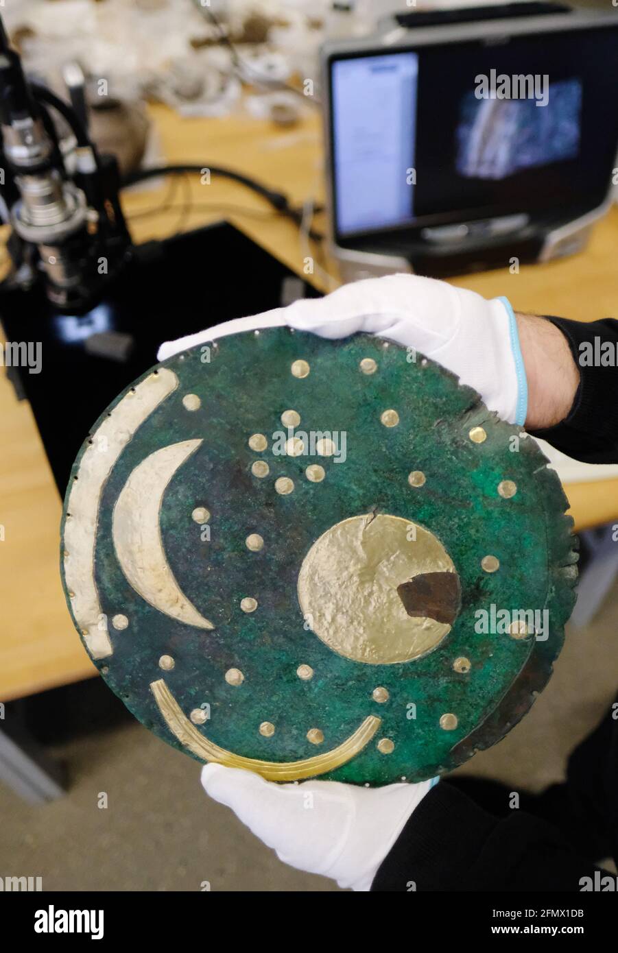 Halle, Germany. 12th May, 2021. A scientist holds the Nebra Sky Disk in ...