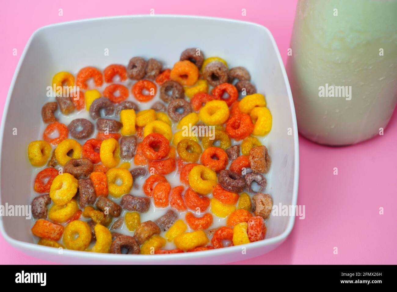 Top view of a bowl of colorful children's cereal and milk on a pink ...
