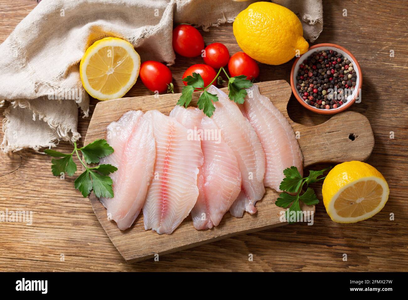 fresh fish fillet of tilapia with ingredients for cooking on wooden board, top view Stock Photo ...