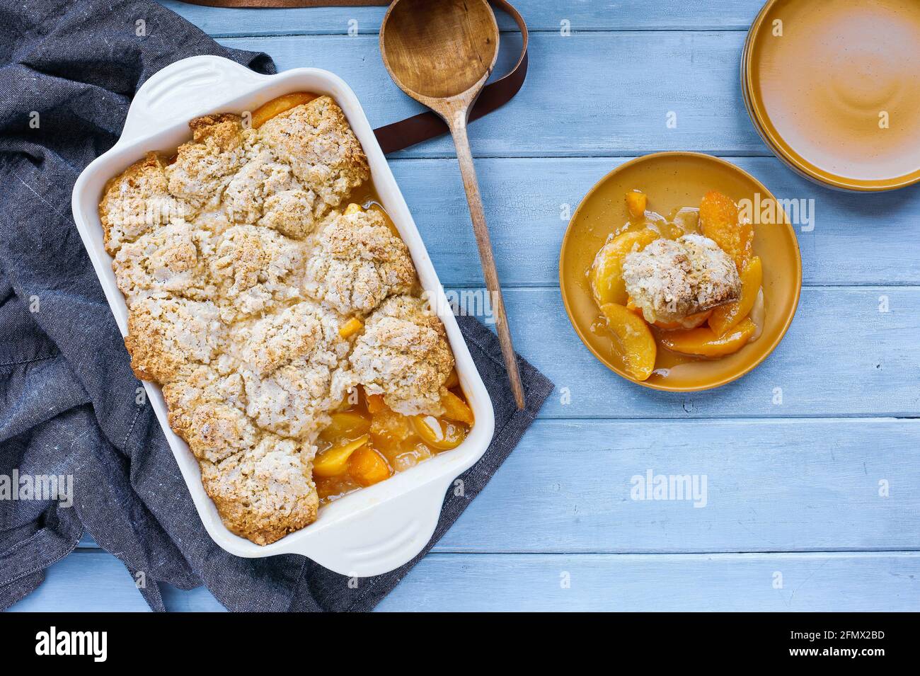 Serving of freshly baked drop biscuit peach cobbler with apron and ...