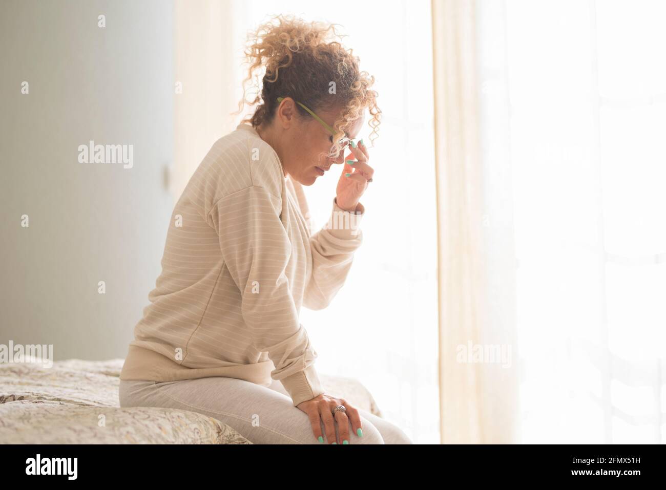 Woman suffering from stress or a headache grimacing in pain sitting on ...