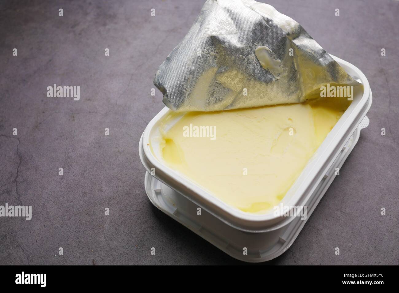salted butter in a container on black background Stock Photo - Alamy