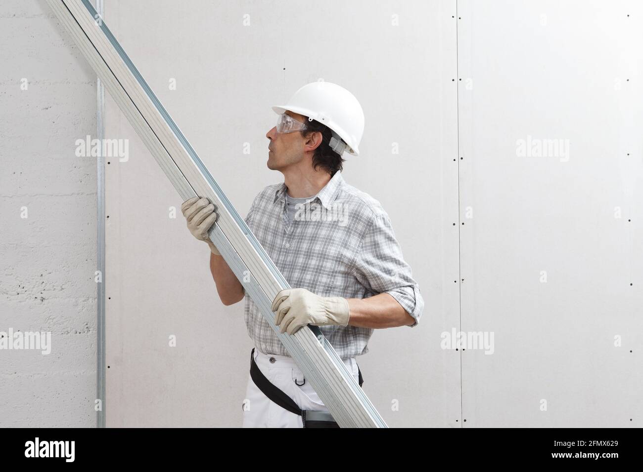 man worker with drywall metal profiles for installing plasterboard ...