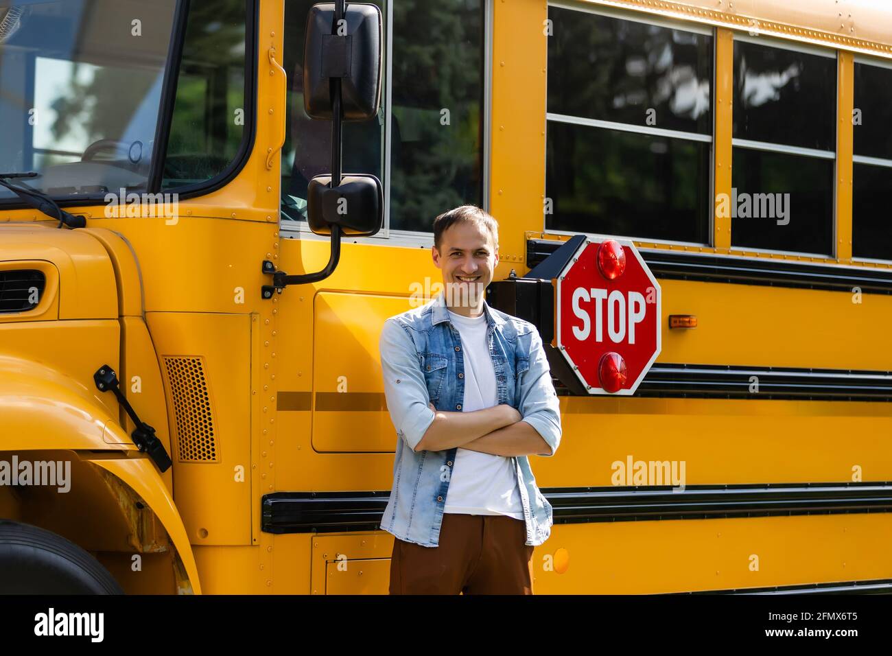 Smiling bus driver looking at camera outside the elementary school ...