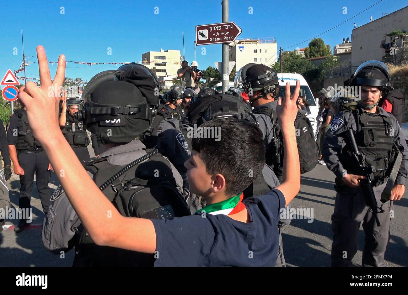 A Palestinian boy marks the victory sign in front of police during a ...