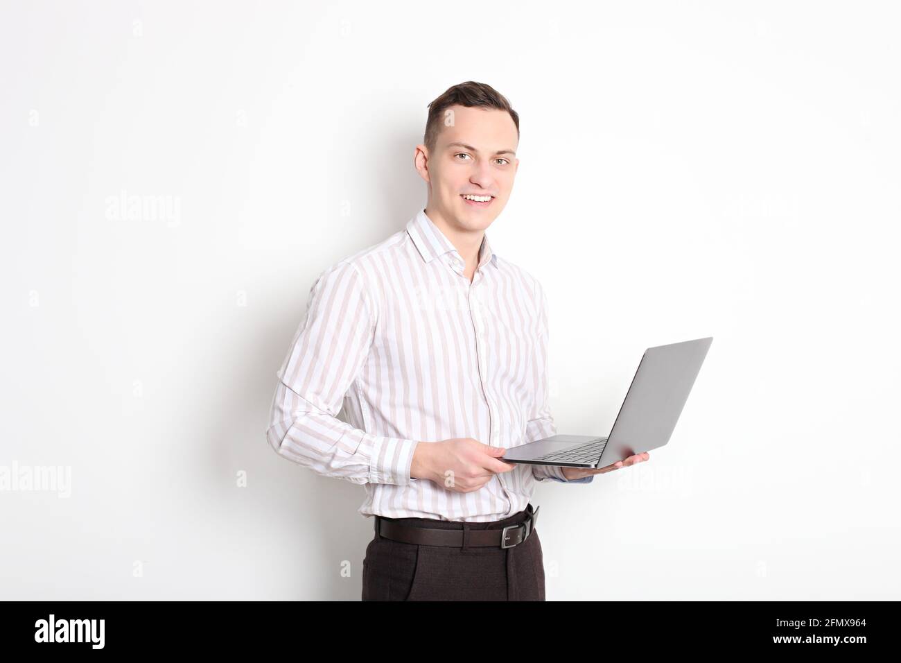 Handsome young man in business suite holding hipster laptop computer ...
