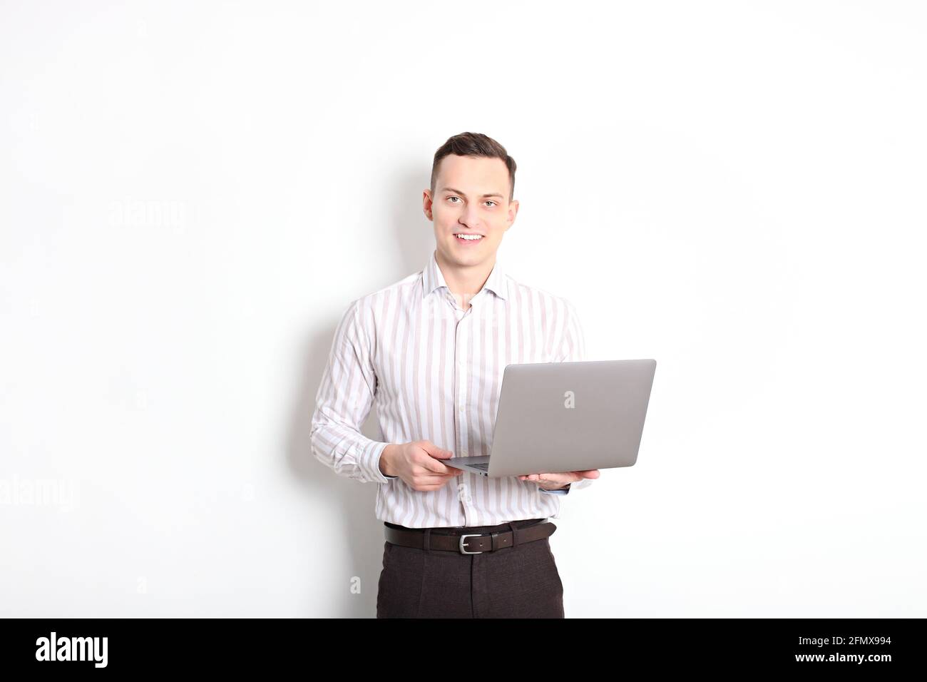 Handsome young man in business suite holding hipster laptop computer ...