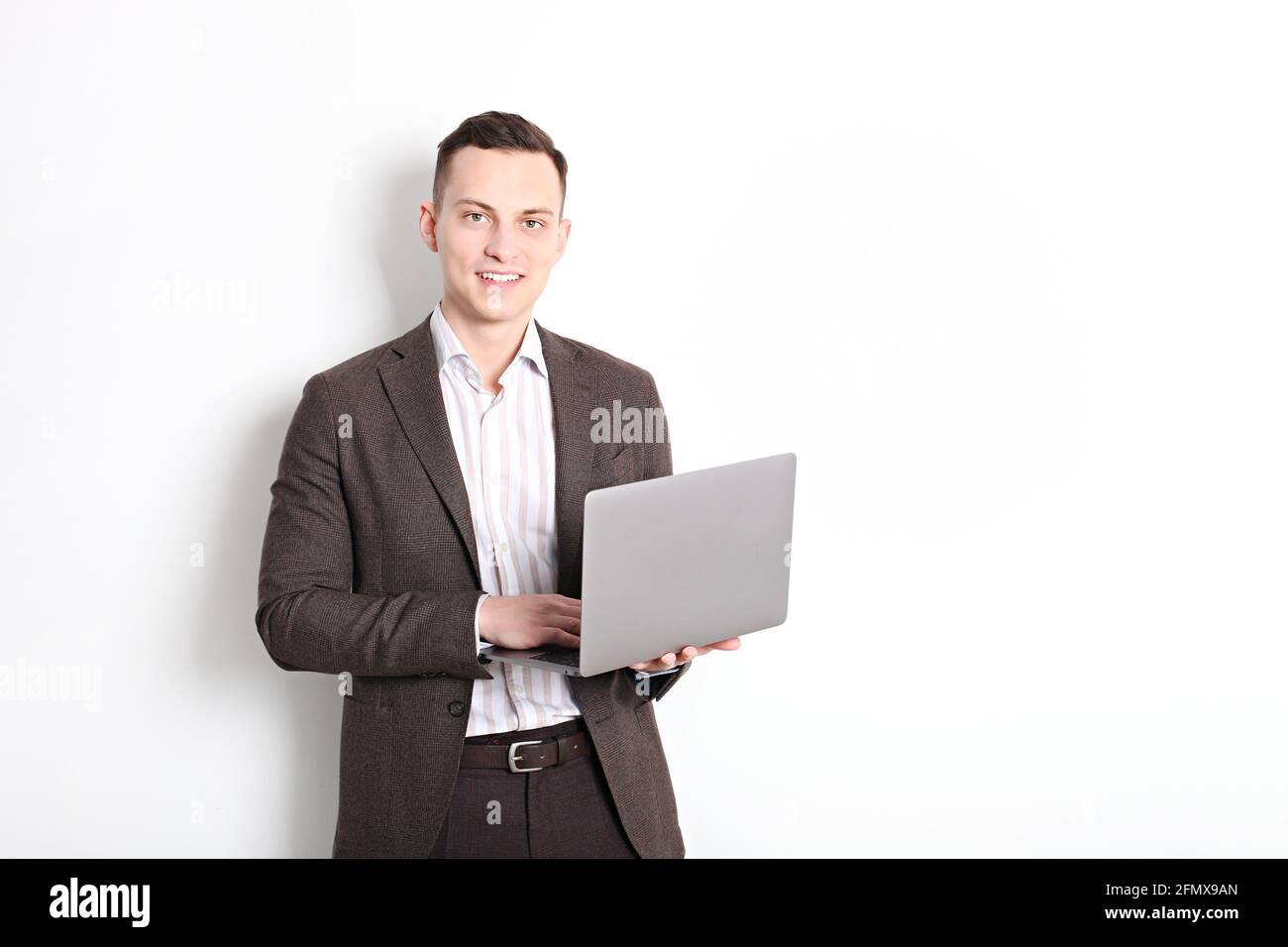 Handsome young man in business suite holding hipster laptop computer ...