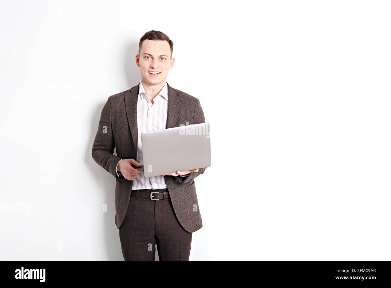 Handsome young man in business suite holding hipster laptop computer ...