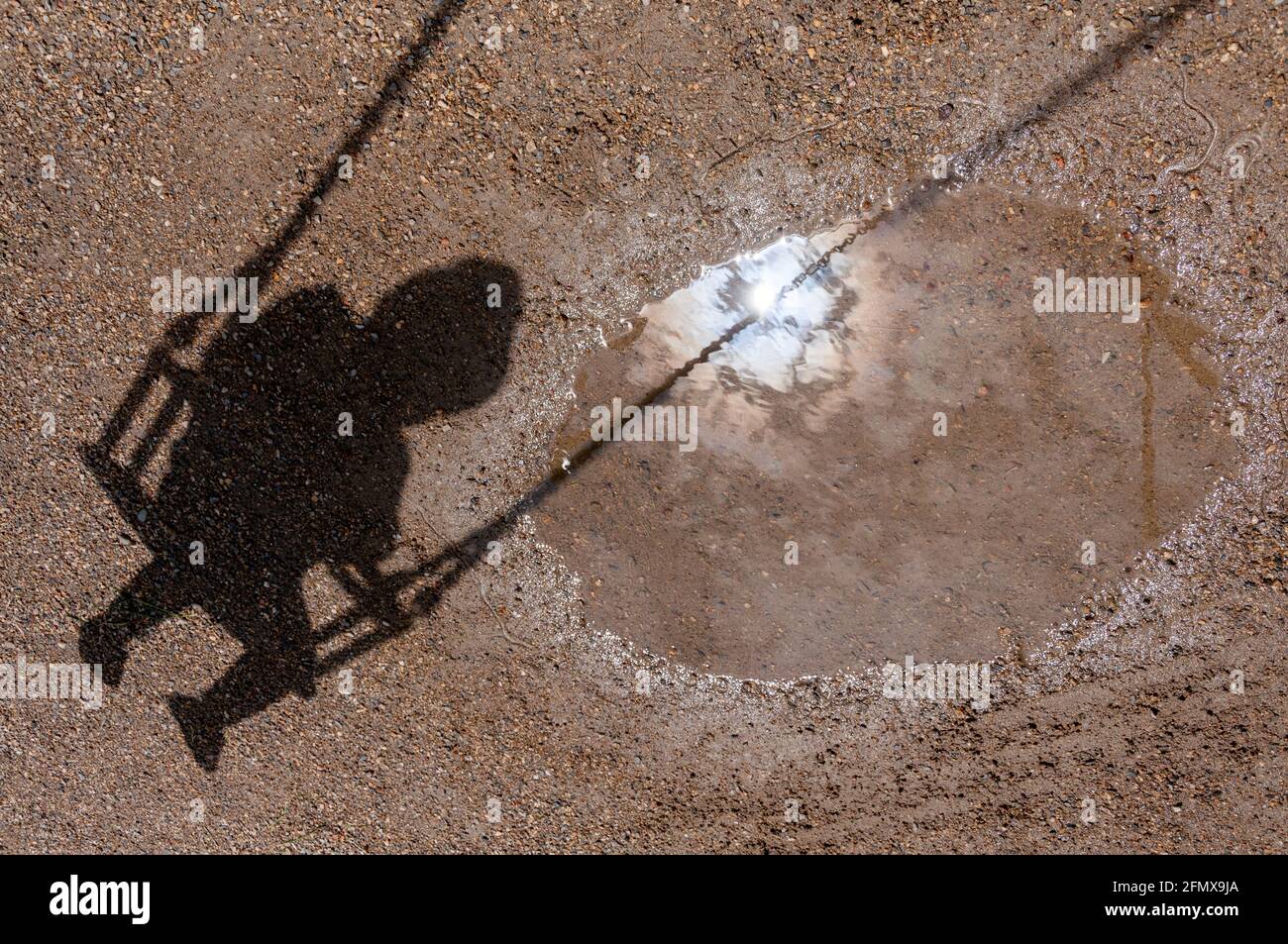 The shadow of a child on a swing. The sun is reflected in a puddle. Kid ...