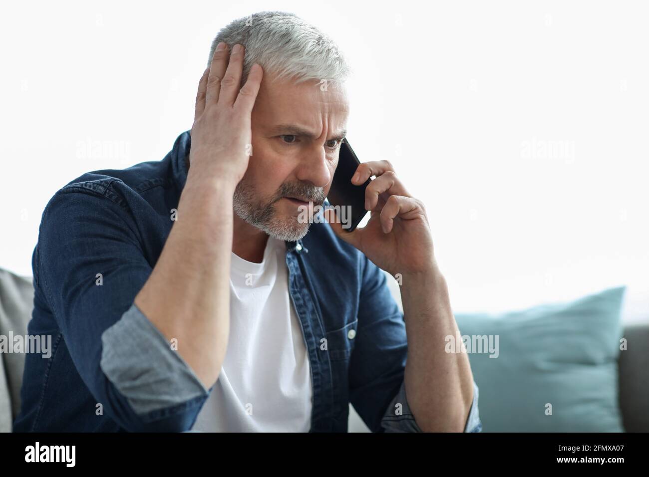 Worried elderly man having phone conversation, touching his head Stock ...