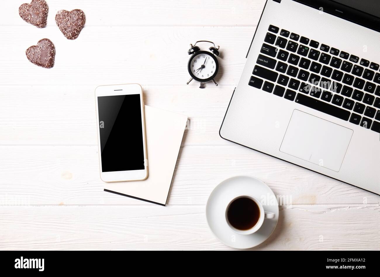 Flat lay on white wooden workspace with laptop computer, cell phone ...
