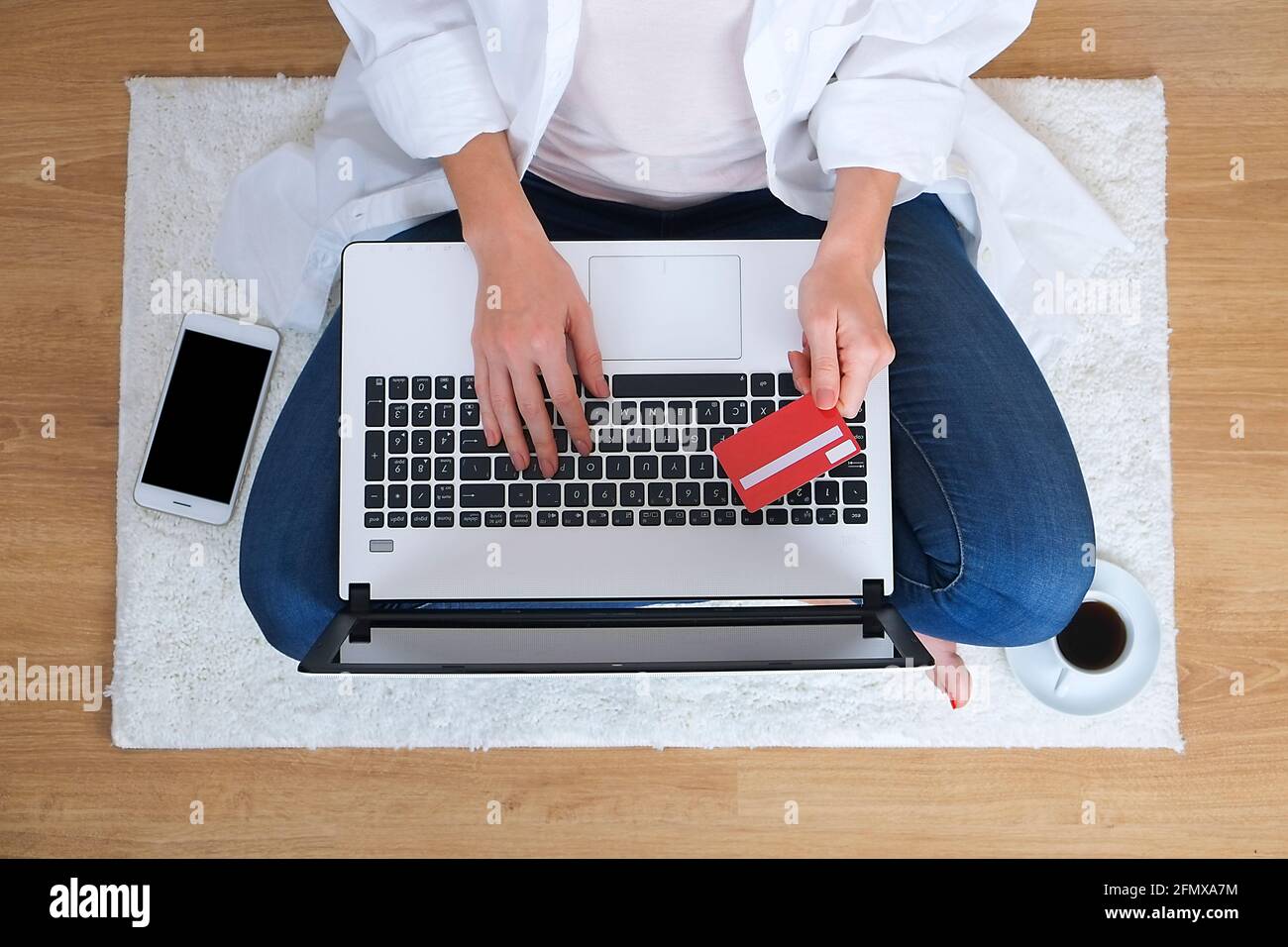 Top view of young woman with laptop & cellphone on her lap, sitting on ...