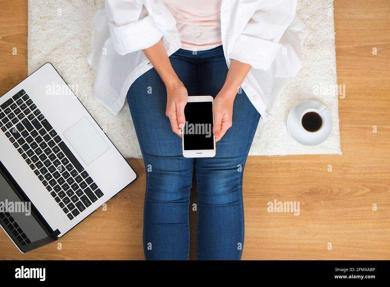 Top view of young woman with laptop & cellphone on her lap, sitting on ...