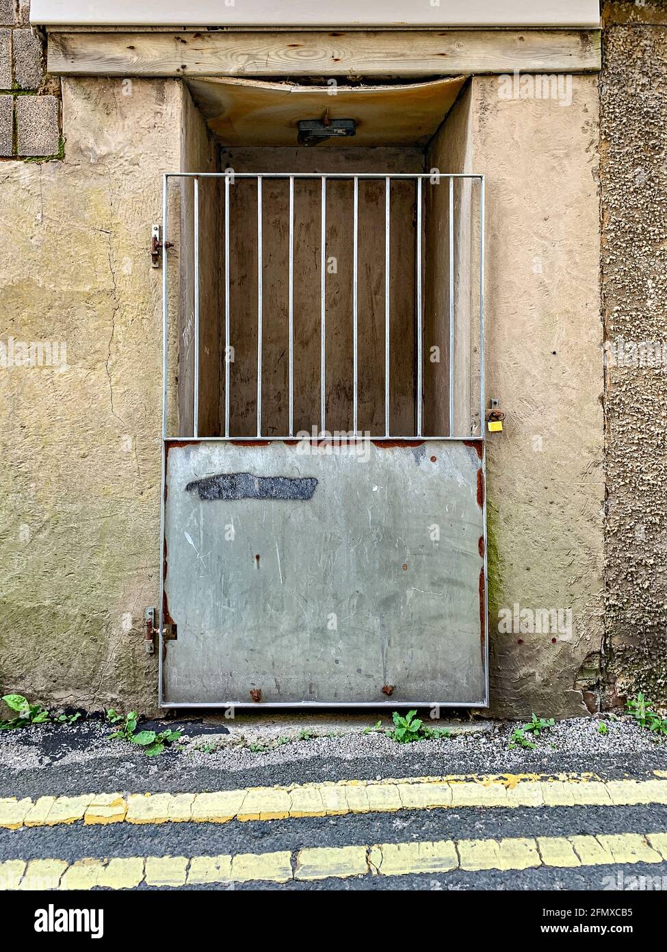 Padlocked metal gate across entrance to boarded up alleyway between ...