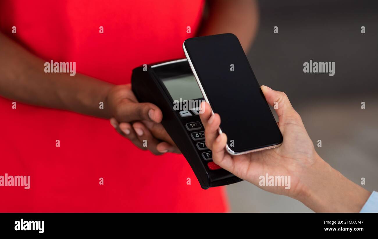 Black delivery man in uniform holding POS machine for payment Stock ...