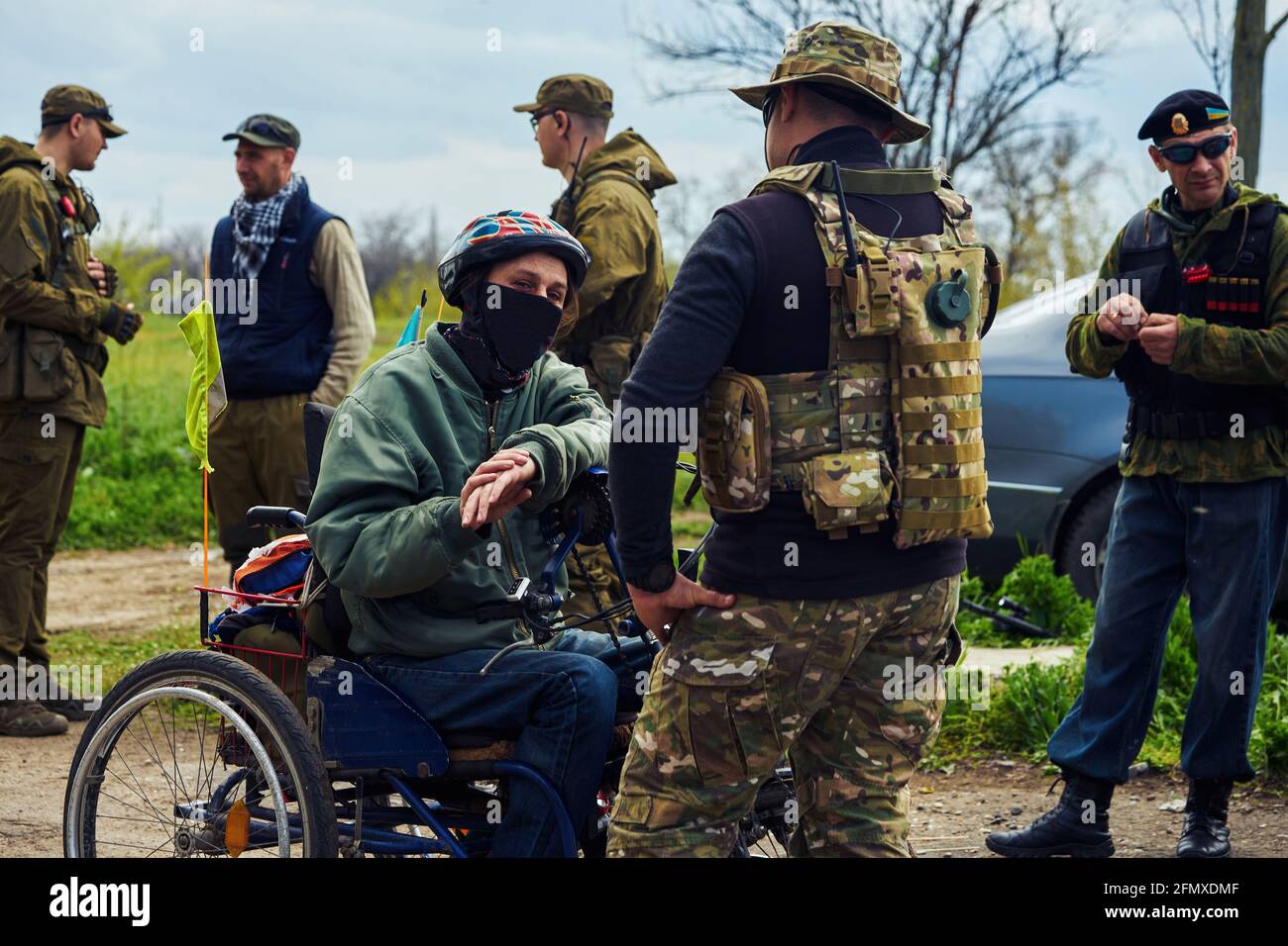 Young disabled man in a wheelchair with a group of soldiers in military ...