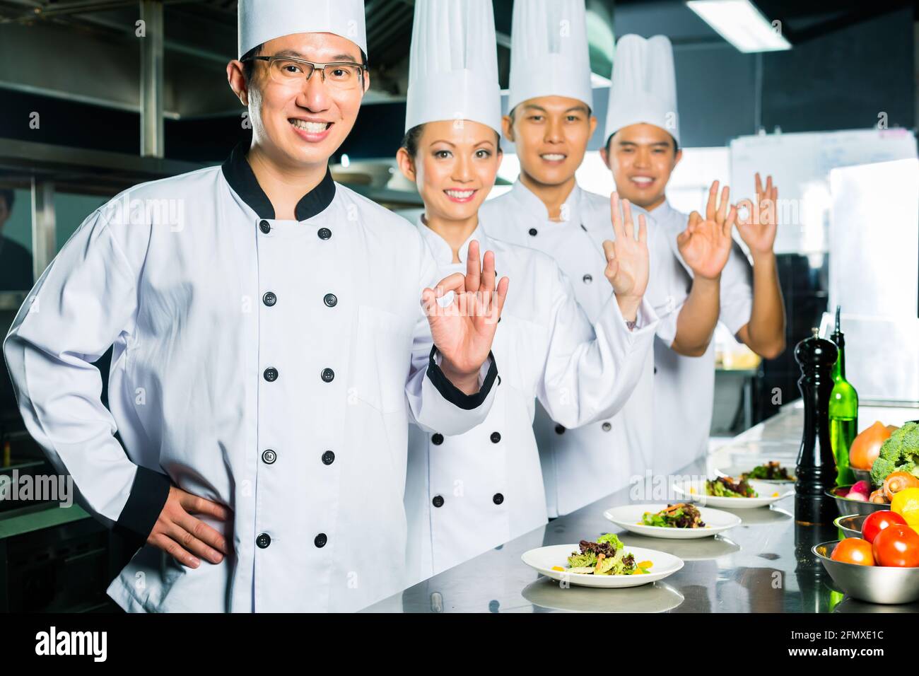 Asian Chef in restaurant kitchen cooking and finishing dishes Stock ...