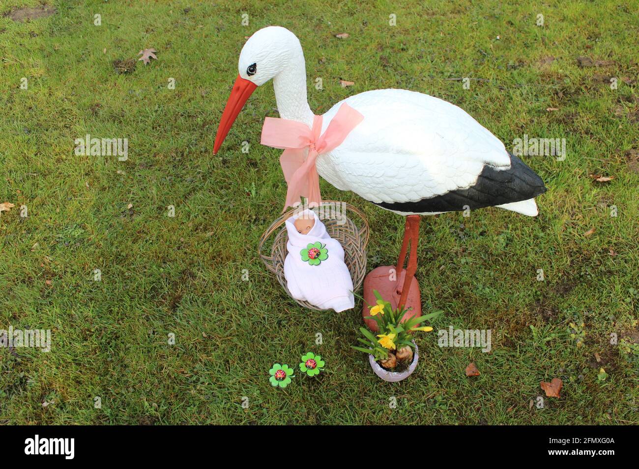 Closeup shot of a Rattle stork with a baby doll in a basket in the ...
