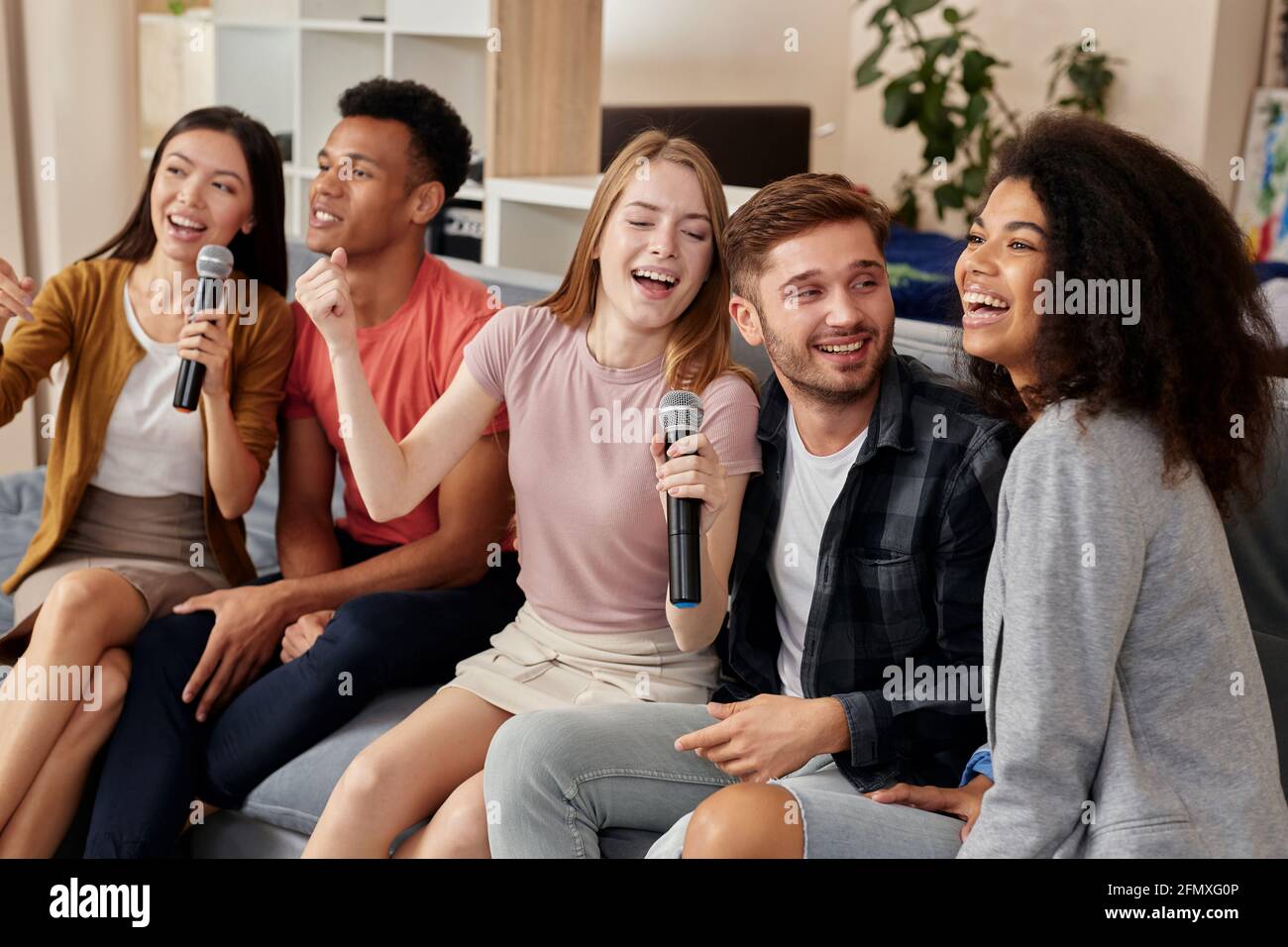 Enjoy with music. Smiling friends looking excited while playing karaoke ...