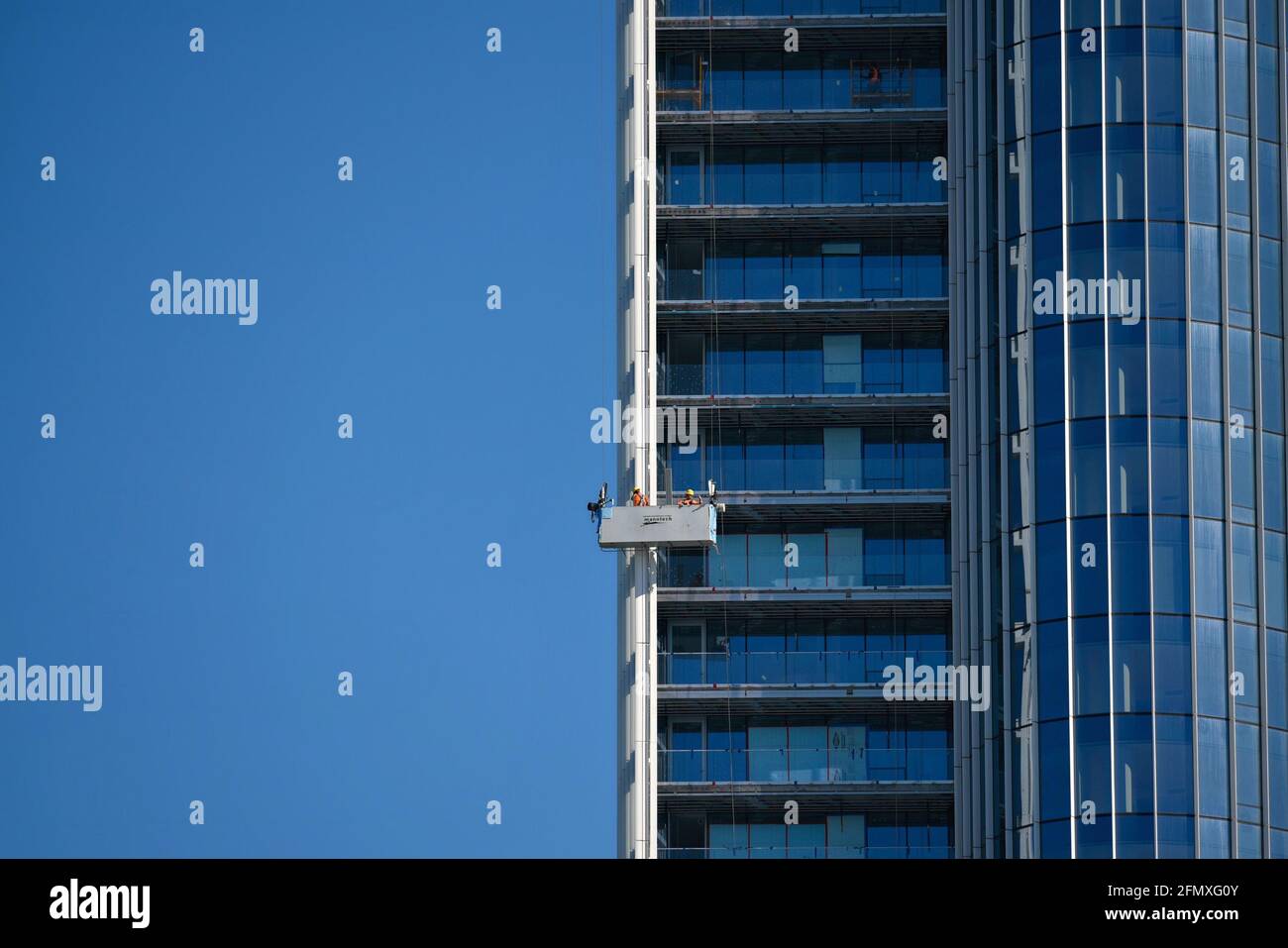 High-rise building facade with a window cleaning crew on a suspended ...