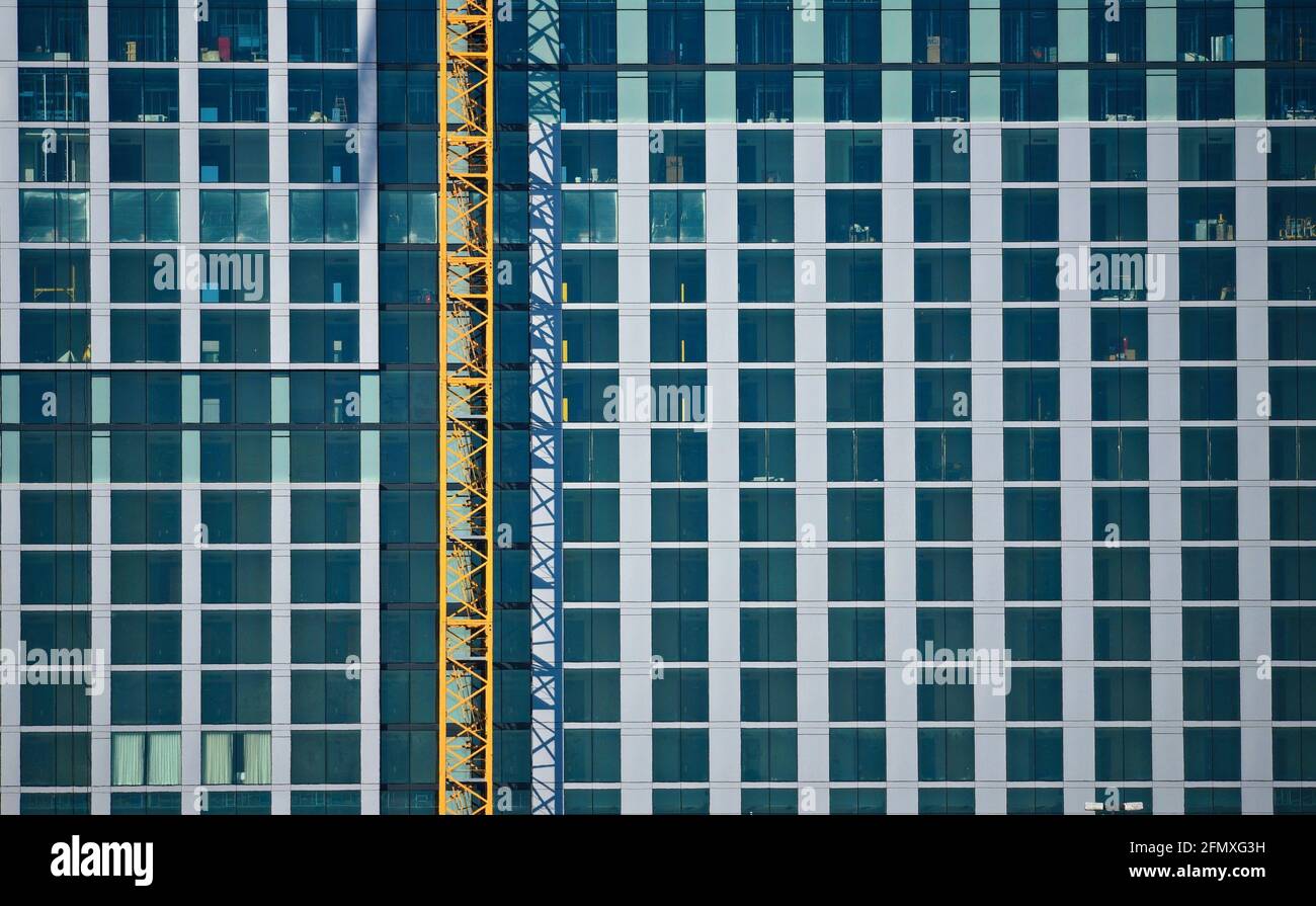 High-rise building symmetrical glass windows facade with a yellow hoist ...