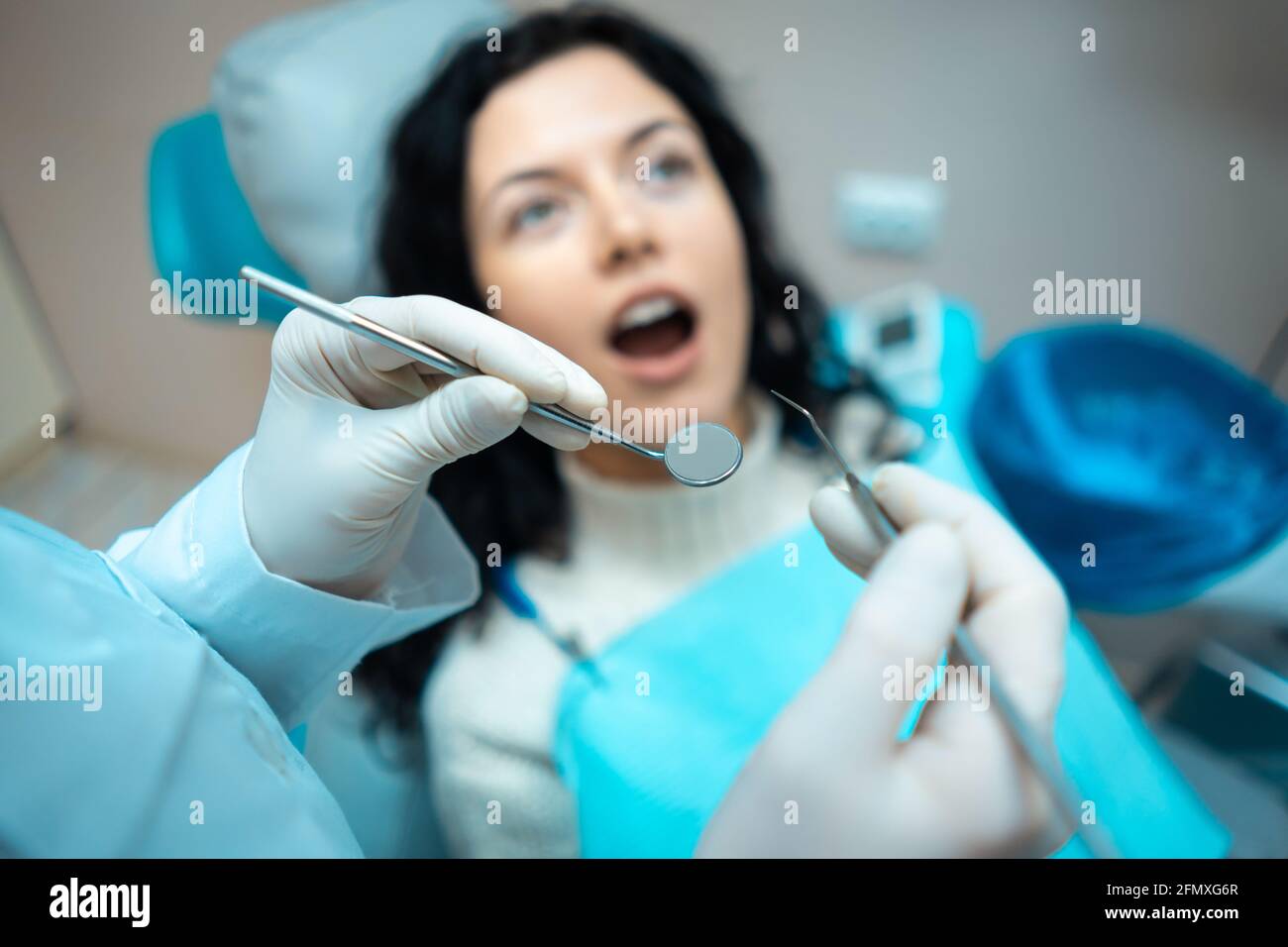 beautiful brunette curly female dentist treat patient in modern clinic ...
