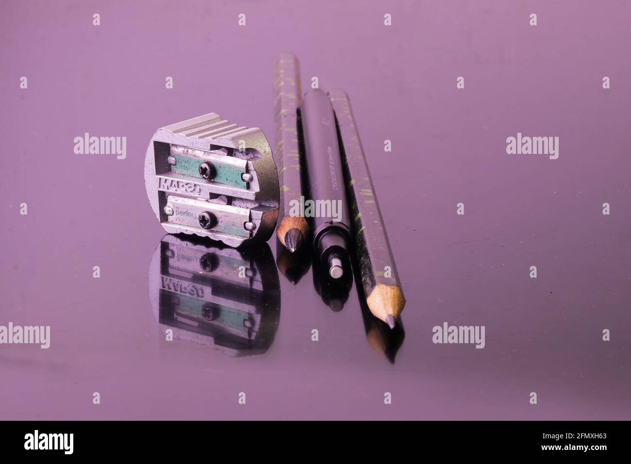 Closeup shot of a pencil sharpener and pencils on the purple background ...