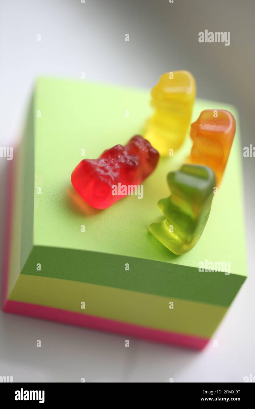 Close-up of four colourful Gummy Bears on top of a pad of sticky note ...