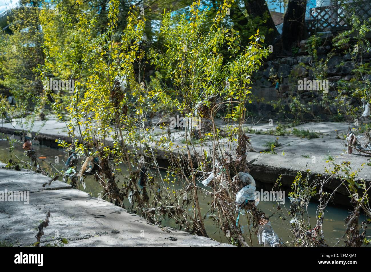 garbage, plastic bags and waste on industrial city river after spring ...