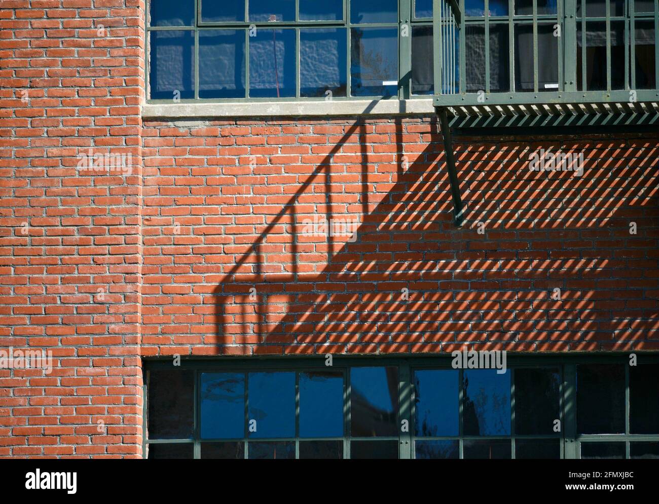 Old Colonial building with the iron railing shadow on the brick facade ...