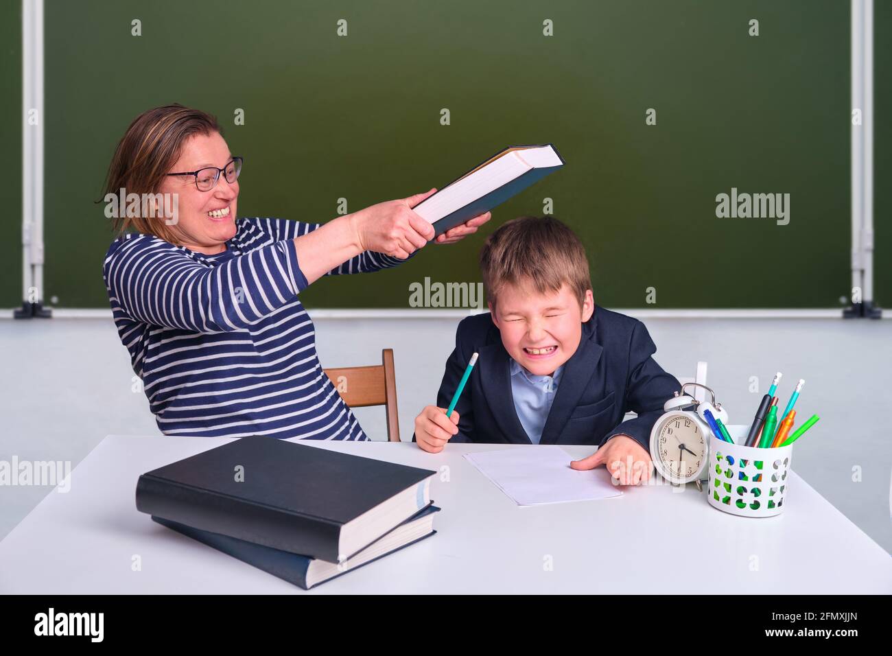 Angry teacher hits a schoolboy with a book in the classroom at the ...