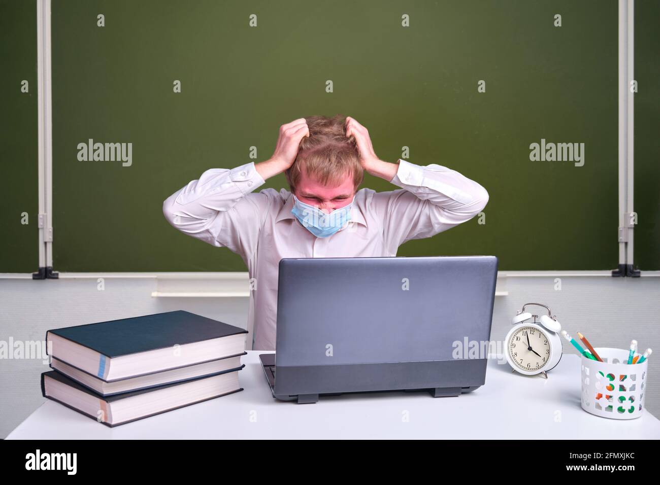 Angry sudent in a classroom with a red face tearing his hair with his ...