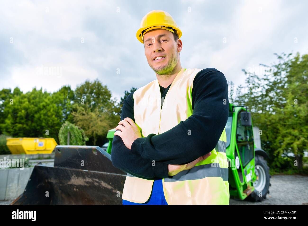 Builder or driver standing in front of construction machinery on ...
