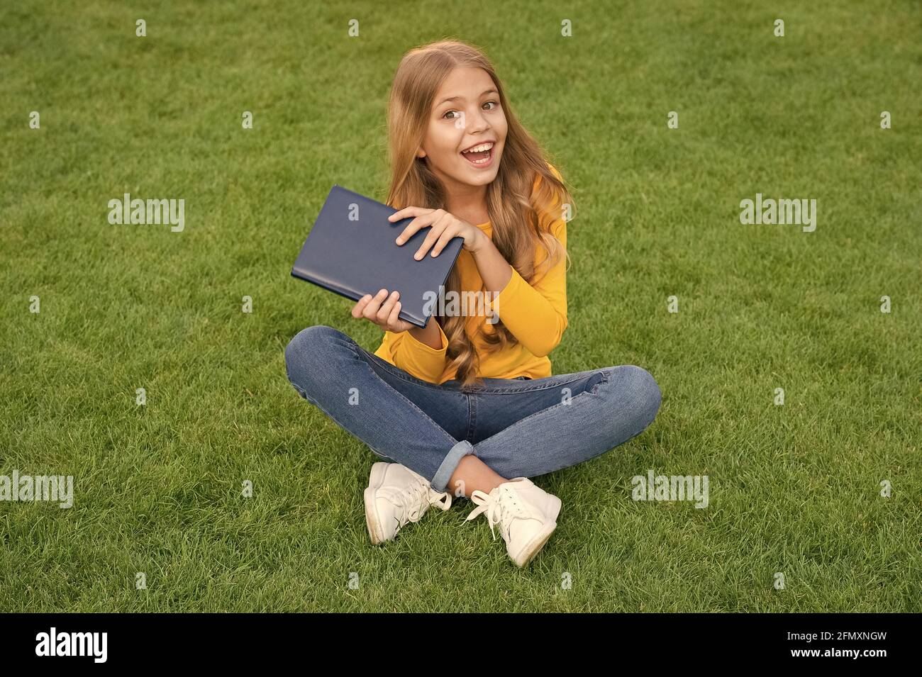 write childhood memories. kid read book in park. happy little girl ...