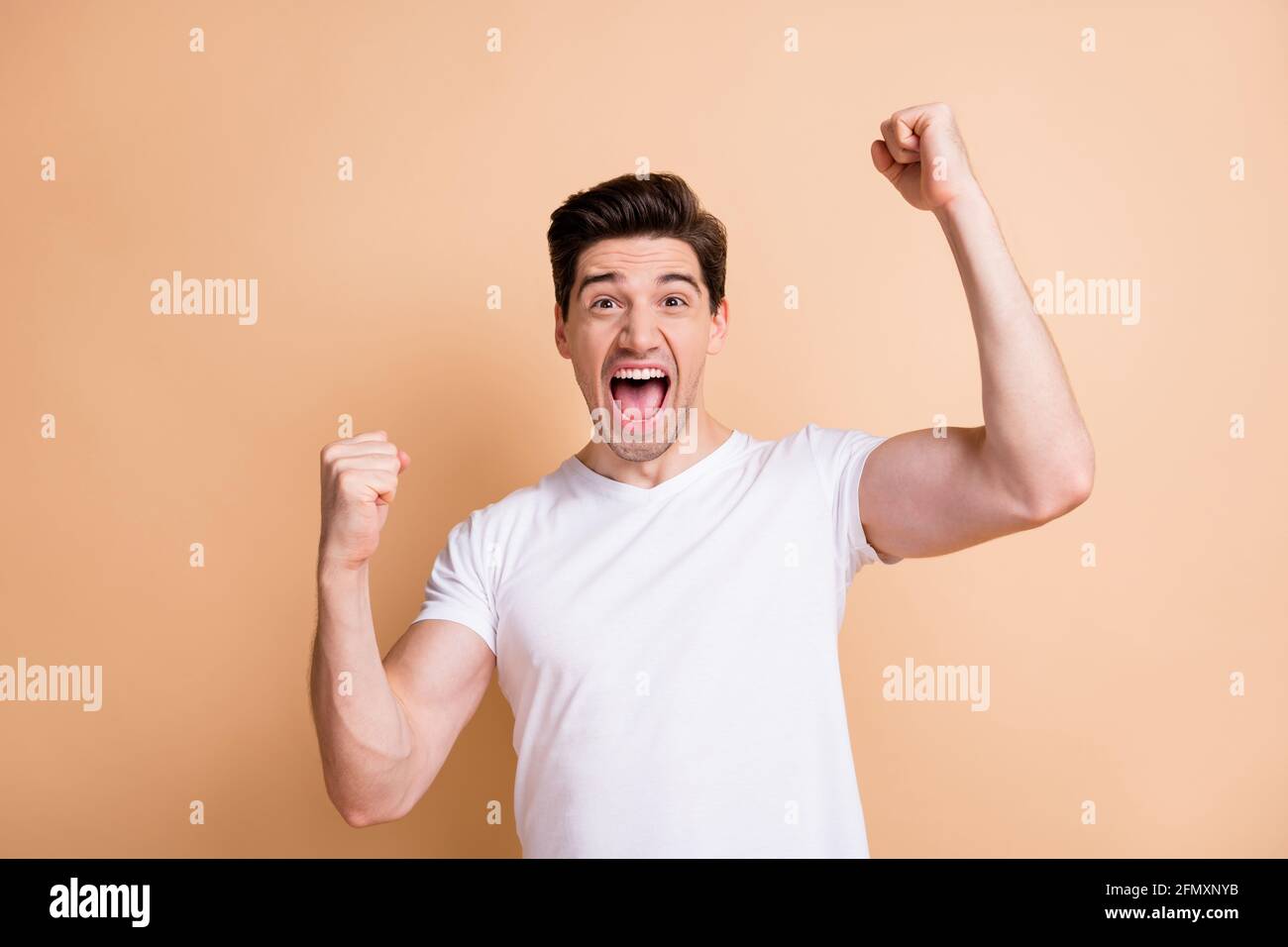 Photo of victorious happy guy raise fists achieve goal scream yeah ...