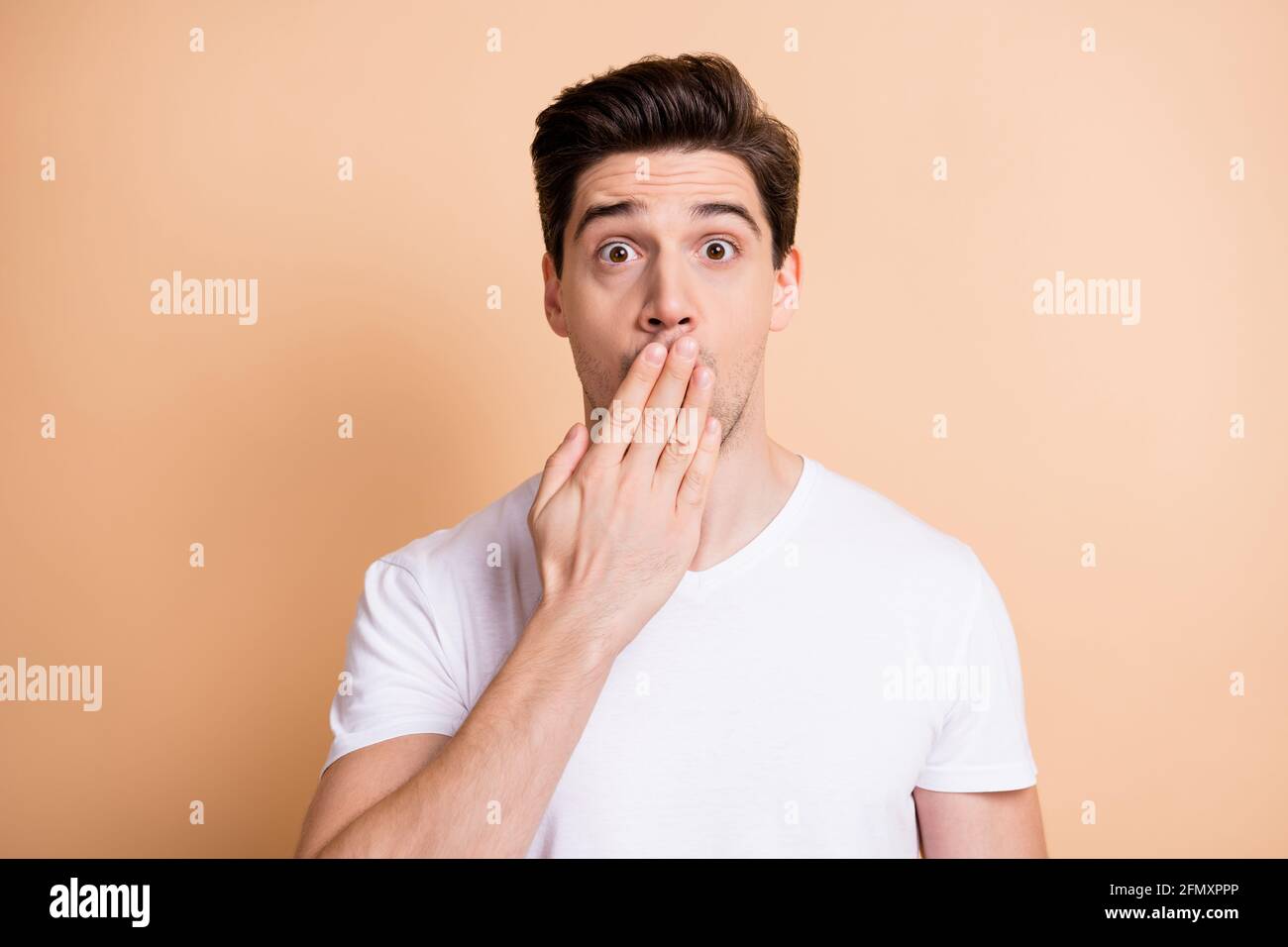 Photo of guilty shocked young man hold hand cover mouth tell secret ...