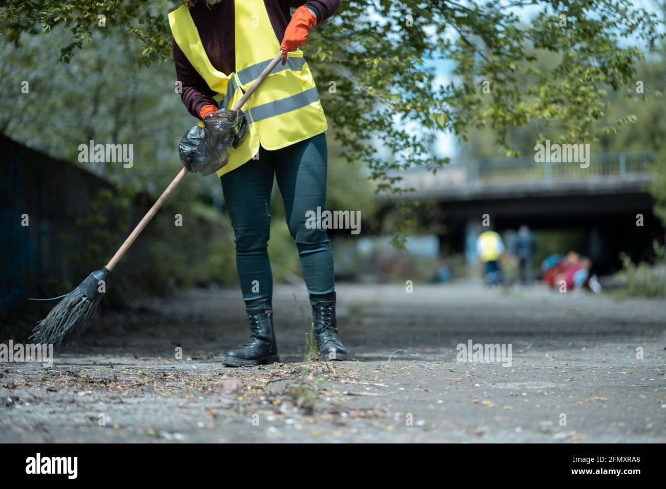 pretty volunteer female cleaning up park from dust waste and foliage ...