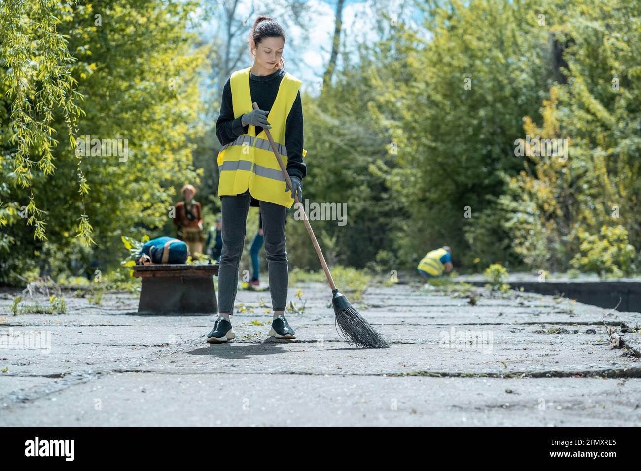 pretty volunteer female cleaning up park from dust waste and foliage ...