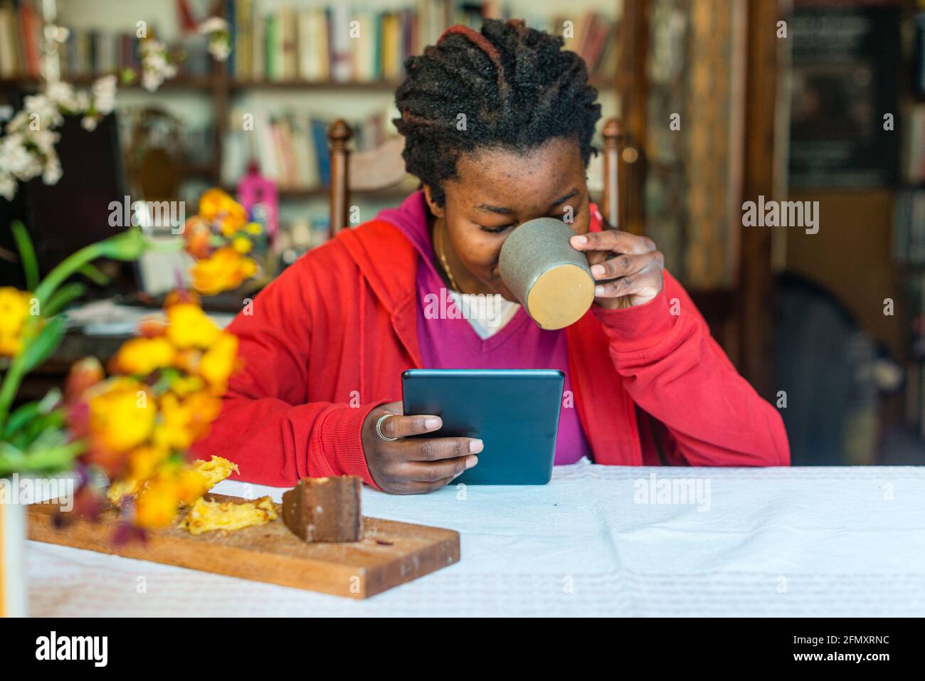 Black Italian woman using a tablet while drinking a coffee Stock Photo ...