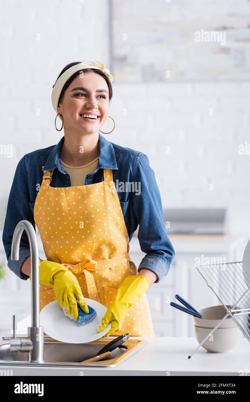 Cheerful woman washing utensil near kitchen sink Stock Photo - Alamy