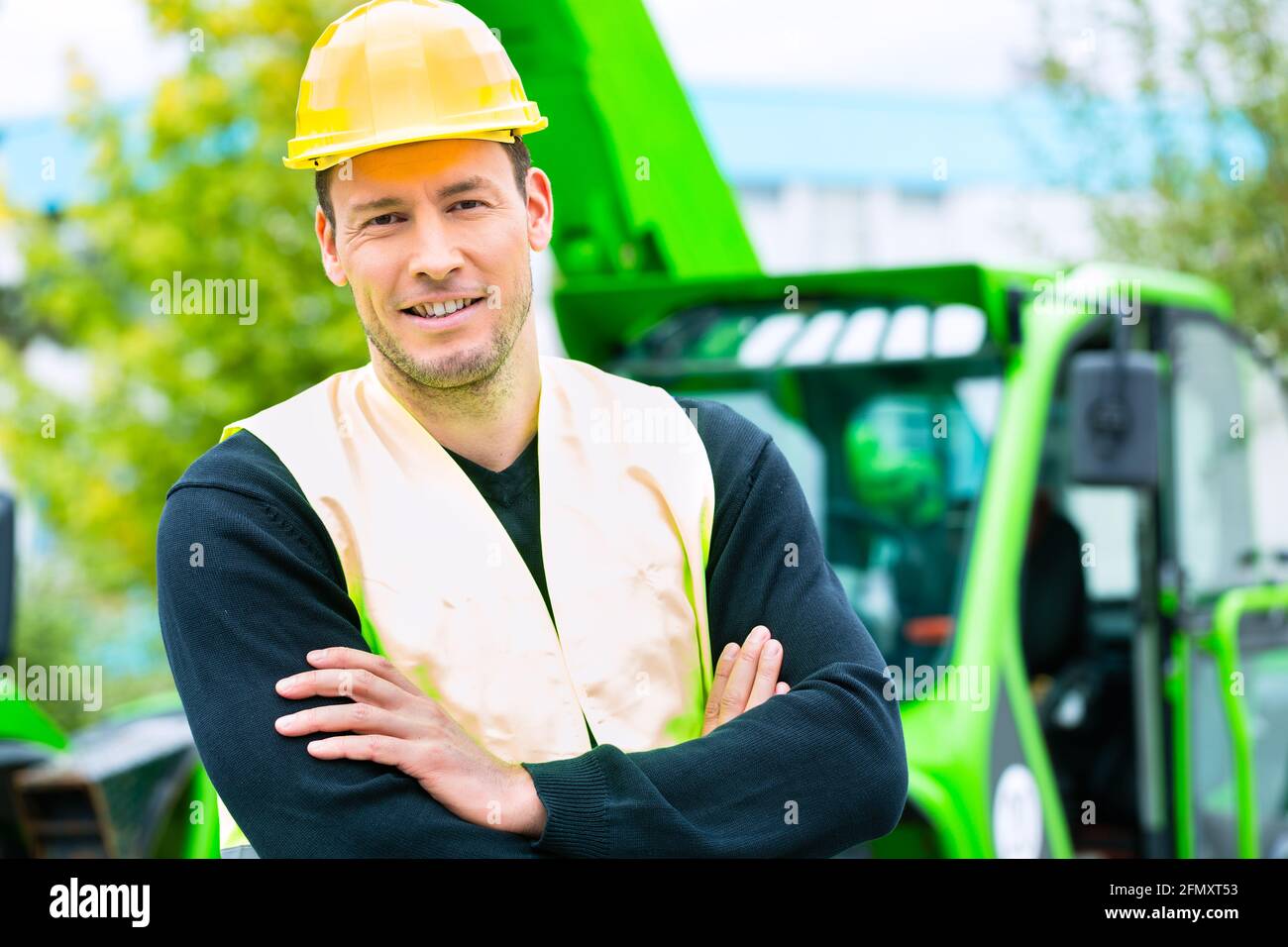 Builder or driver standing in front of construction machinery on ...